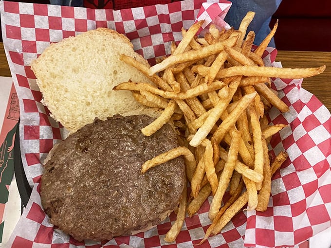 The burger arrives on classic red-checkered paper—a juicy masterpiece with golden fries that would make fast food chains weep with inadequacy.