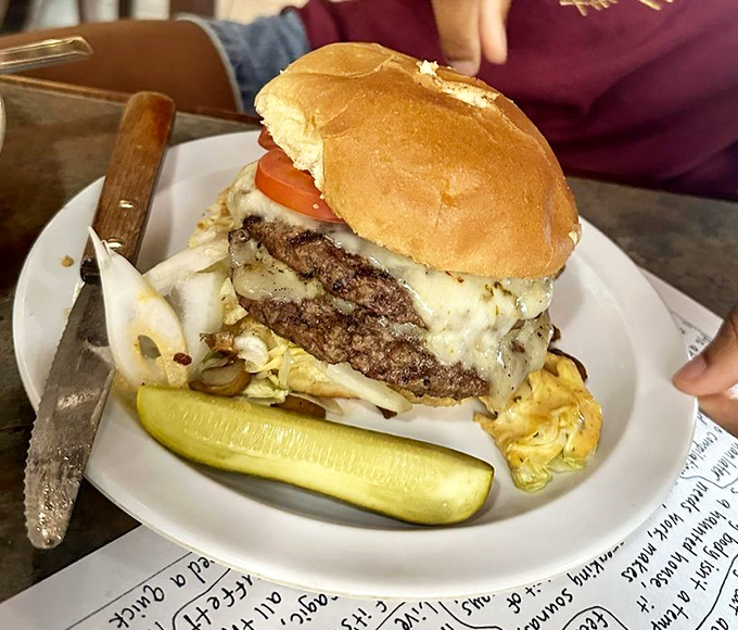 This isn't just a burger—it's a towering monument to beef artistry. The pickle stands guard, knowing you'll need reinforcements to tackle this beauty. 
