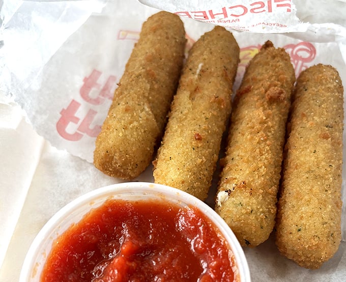Golden-fried mozzarella sticks—crunchy armor protecting molten cheese treasure within. The marinara dipping sauce is just the sidekick they deserve.