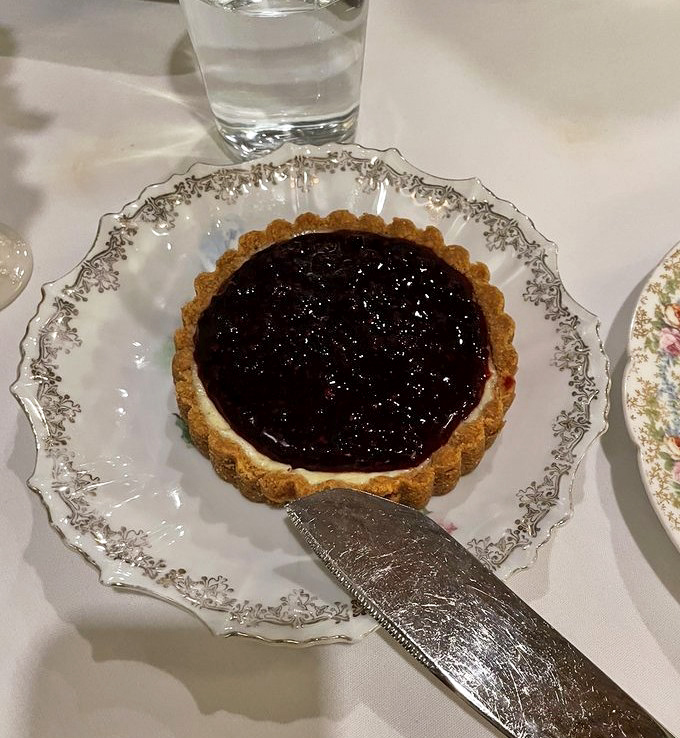 Cheesecake tart perfection on vintage china – the kind of dessert that makes conversation stop and eyes close in silent appreciation.