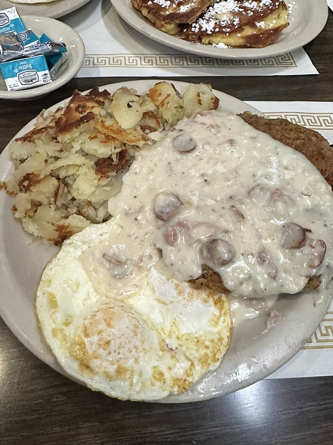 Country gravy cascading over chicken fried steak with those legendary potatoes—a plate that says "you won't need lunch" in the most delicious way possible.