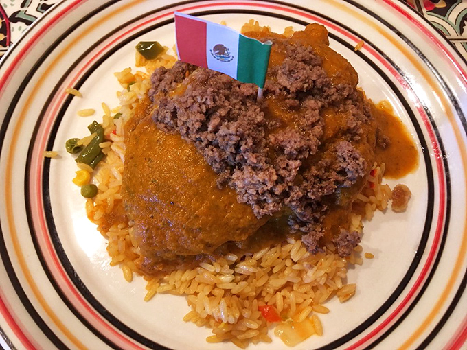That's not just a chile relleno—it's a Mexican flag-topped masterpiece resting on a bed of rice that clearly didn't come from a box with instructions.