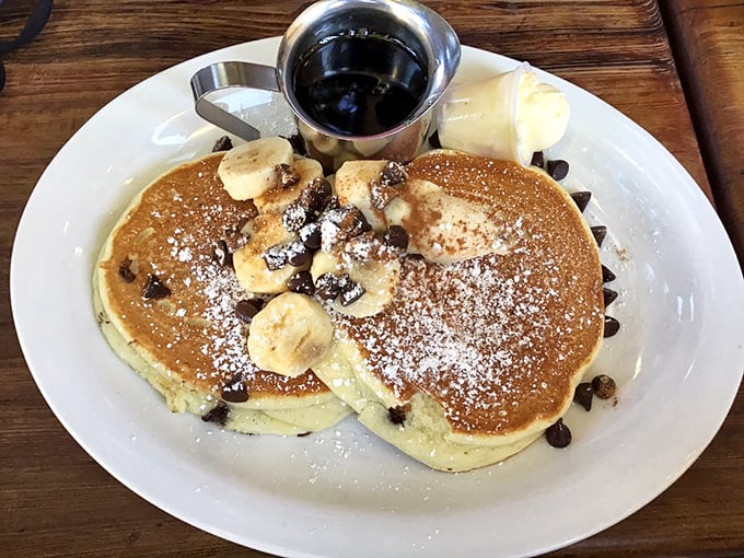These chocolate chip banana pancakes aren't just breakfast, they're therapy – fluffy discs of joy dusted with powdered sugar and topped with nature's candy.