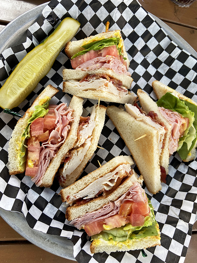 This club sandwich isn't just stacked – it's architected. The pickle stands guard like it knows something special is happening between those layers.