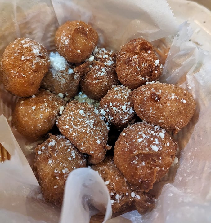 These aren't just hush puppies—they're little golden orbs of cornmeal bliss dusted with powdered sugar, like donut holes that went to seafood school.