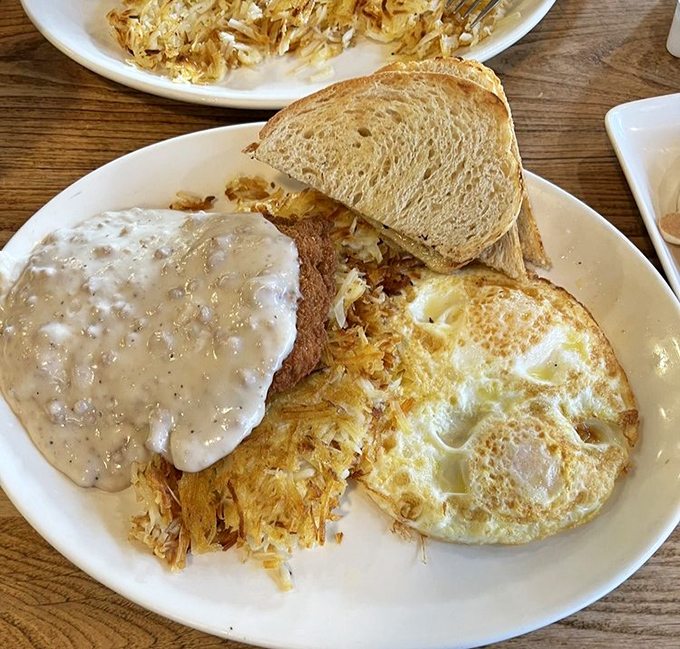 Country fried steak smothered in gravy alongside sunny-side-up eggs—comfort food that whispers, "Go ahead, take that nap later. You've earned it."