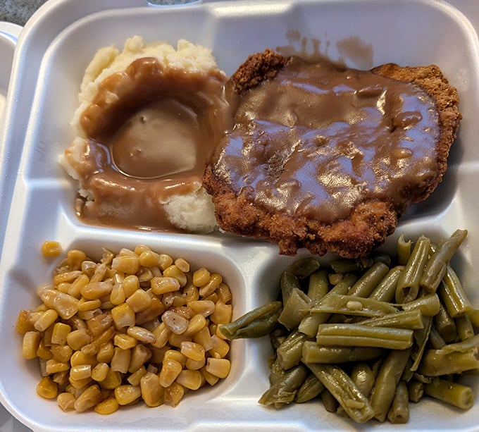 Southern comfort on a plate—country fried steak swimming in gravy alongside creamy corn and green beans. Grandma would approve, then ask for seconds.