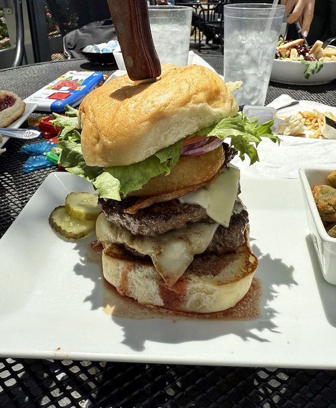 This towering burger achievement should come with its own building permit – layers of beef, cheese, and veggies that defy both gravity and restraint.