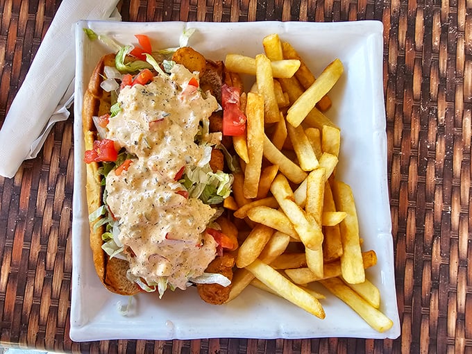 The crab po' boy arrives like a delicious architectural challenge—how to fit that mountain of seafood and slaw into your mouth without wearing half of it home.