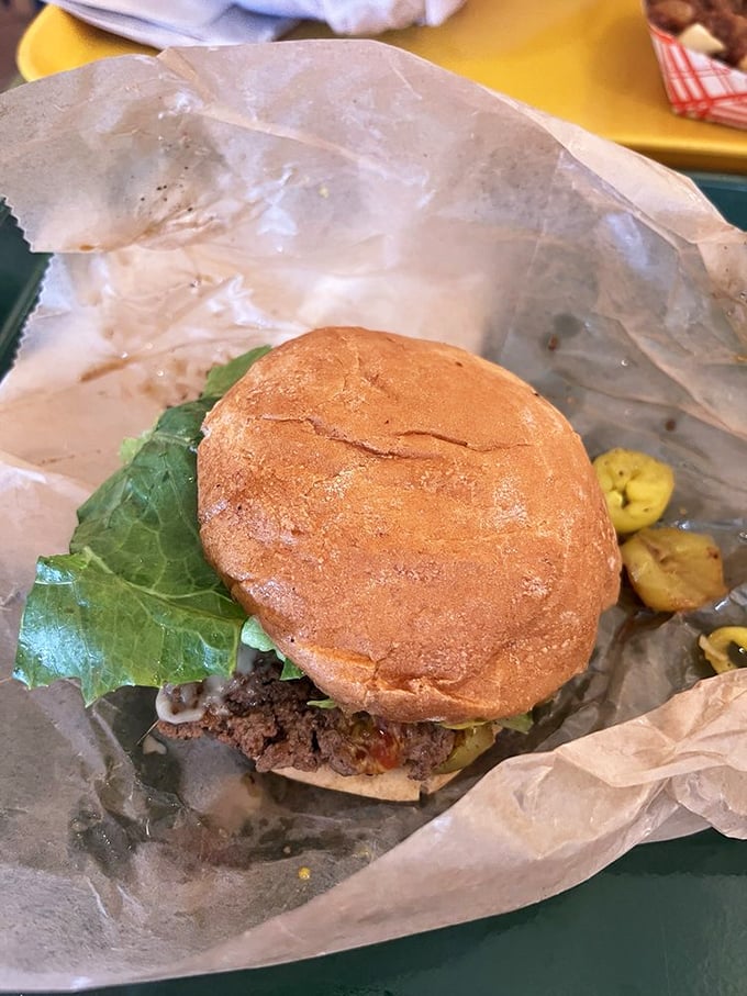 Simplicity on a bun. The humble burger in its natural habitat, nestled on wax paper – no pretension, just pure flavor awaiting discovery.