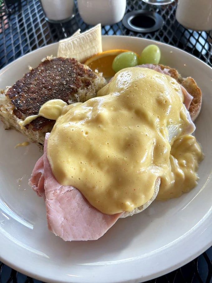 The hollandaise on this Eggs Benedict doesn't just sit there—it lounges luxuriously, draping itself over ham and English muffin with golden confidence.