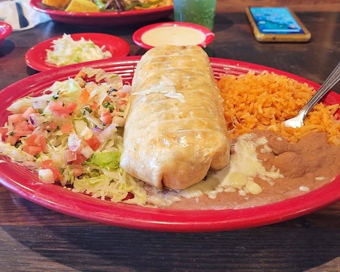 This chimichanga isn't just fried—it's transformed. Resting on that vibrant red plate like royalty, surrounded by its court of rice, beans, and fresh pico de gallo.