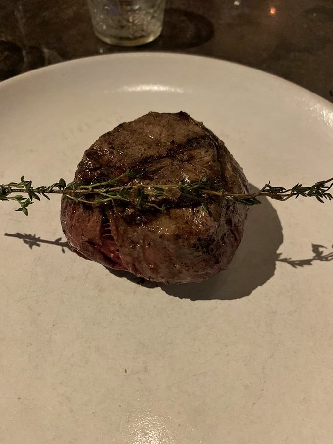 Simplicity at its finest: a perfectly seared filet mignon with a sprig of thyme that's not just garnish—it's a promise of flavor.