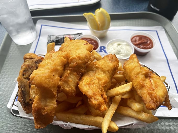 Behold the holy grail of fish and chips—golden batter that shatters like glass, revealing fish so tender it practically surrenders to your fork.