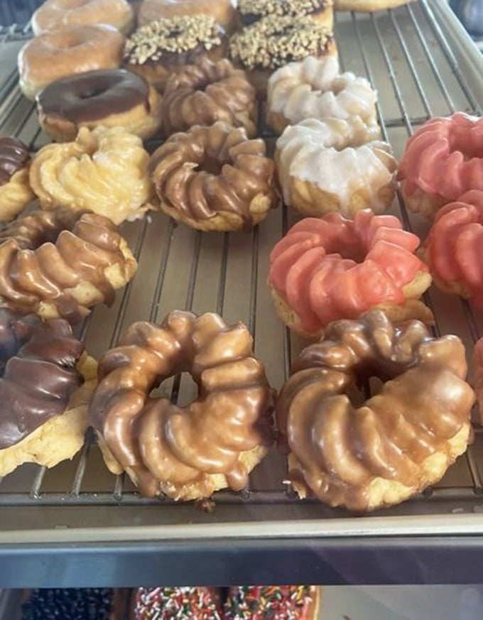 French crullers lined up like edible art—their ridged exteriors glistening with glaze, waiting to dissolve on your tongue.