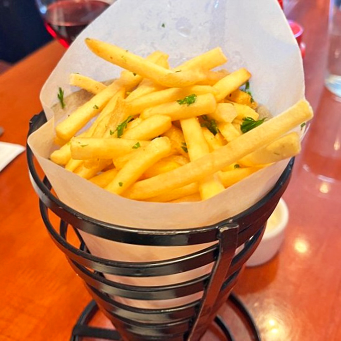 French fries so perfectly golden they deserve their own spotlight, served in a metal basket like edible treasure.