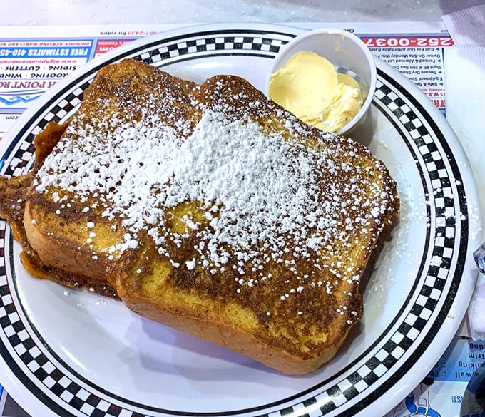 This French toast doesn't just arrive—it makes an entrance, dusted with powdered sugar like fresh snow on a delicious landscape.