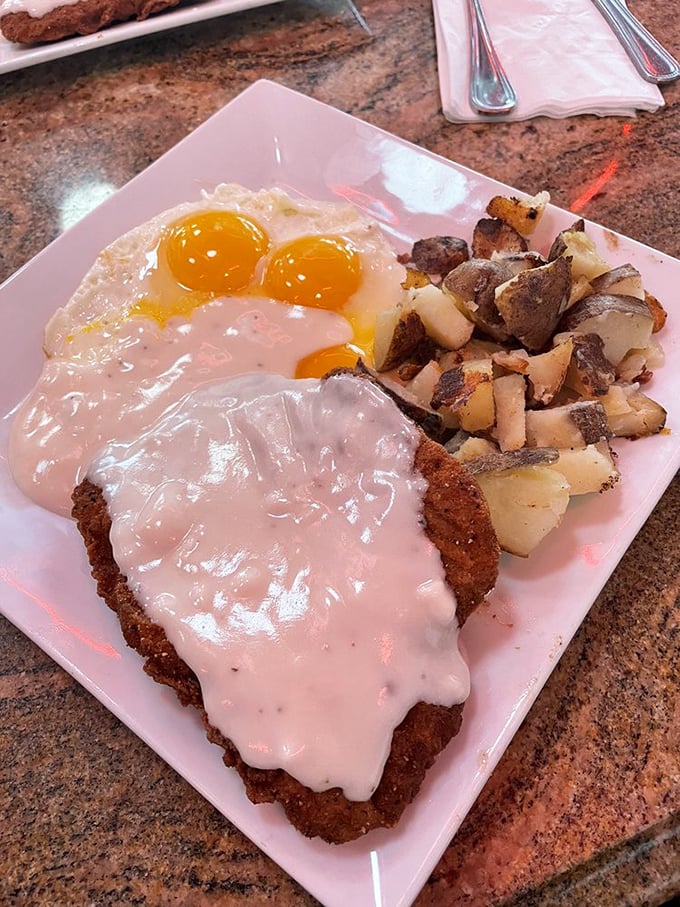 Country fried steak smothered in gravy with sunny-side eggs – the kind of breakfast that requires a nap afterward and zero regrets.