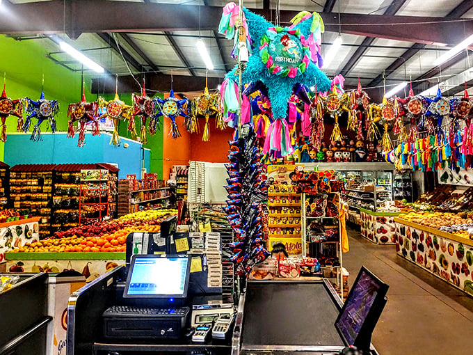 A fiesta for the senses! Colorful piñatas hang above produce displays, creating a vibrant marketplace atmosphere that awakens childhood memories.