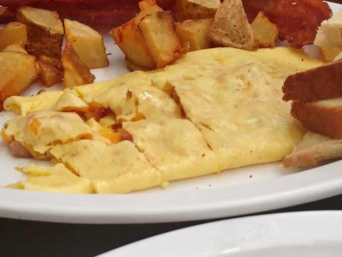 This isn't just an omelet—it's a fluffy yellow canvas painted with melted cheese and paired with home fries that could make a potato farmer weep with joy.
