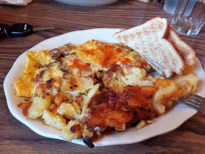 This omelet doesn't just share the plate with home fries – they're dance partners in a breakfast tango that's been perfected over decades.