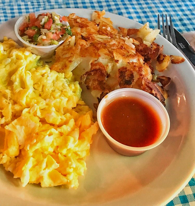 Golden hash browns that crackle with each bite, fluffy scrambled eggs, and what appears to be crispy breakfast perfection on a no-nonsense white plate.