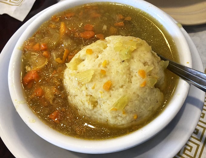 This matzo ball soup doesn't just warm your body—it recalibrates your soul with a baseball-sized dumpling floating majestically in golden broth. 