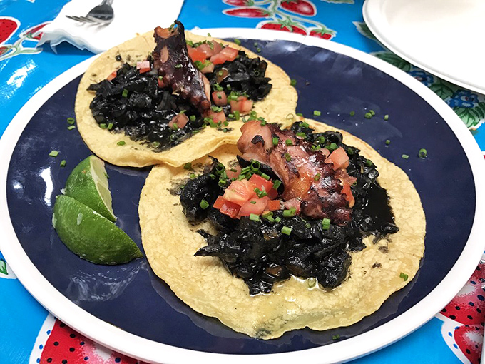 The legendary octopus tacos arrive dramatically on golden tortillas, their tentacles nestled in inky blackness—like the ocean's most delicious secret finally revealed.