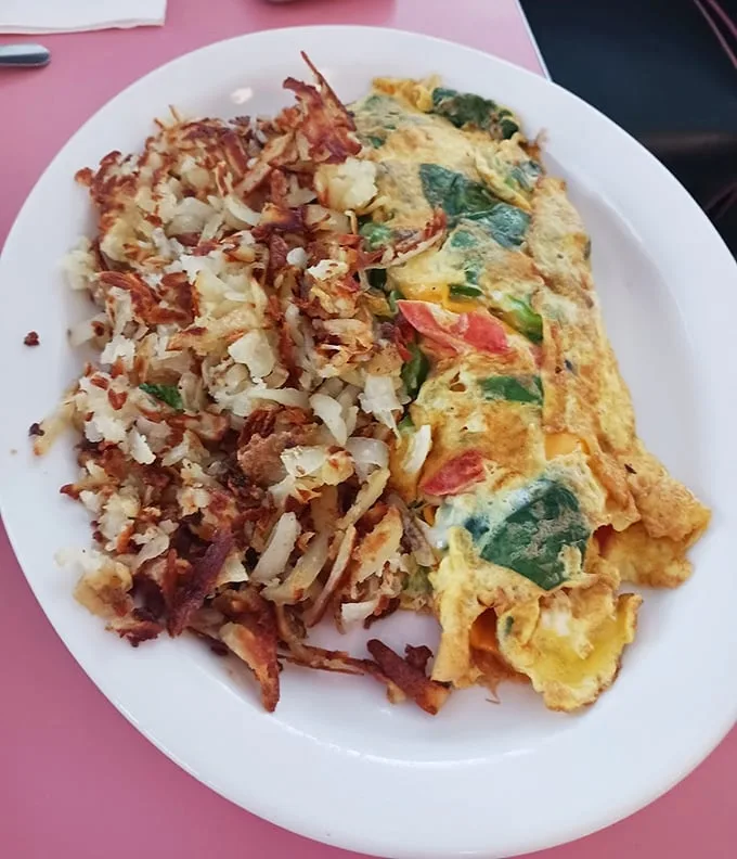 This isn't just an omelet—it's an edible love letter to vegetables, folded into fluffy eggs and served with hash browns that crackle with each bite.
