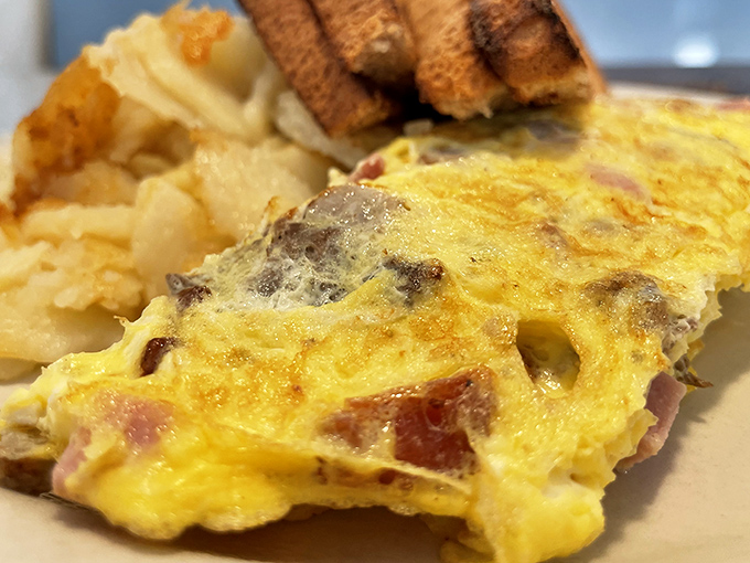 This isn't just an omelet—it's a masterclass in breakfast architecture, where ham and cheese become something greater than the sum of their parts.
