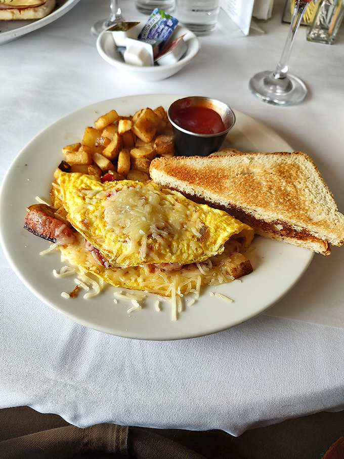 This isn't just any omelet—it's a cheese-draped morning masterpiece. Those home fries deserve their own fan club. 