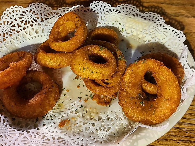 Golden-fried onion rings arrive on delicate doilies – a touch of Southern gentility for a humble dish elevated to crispy perfection.