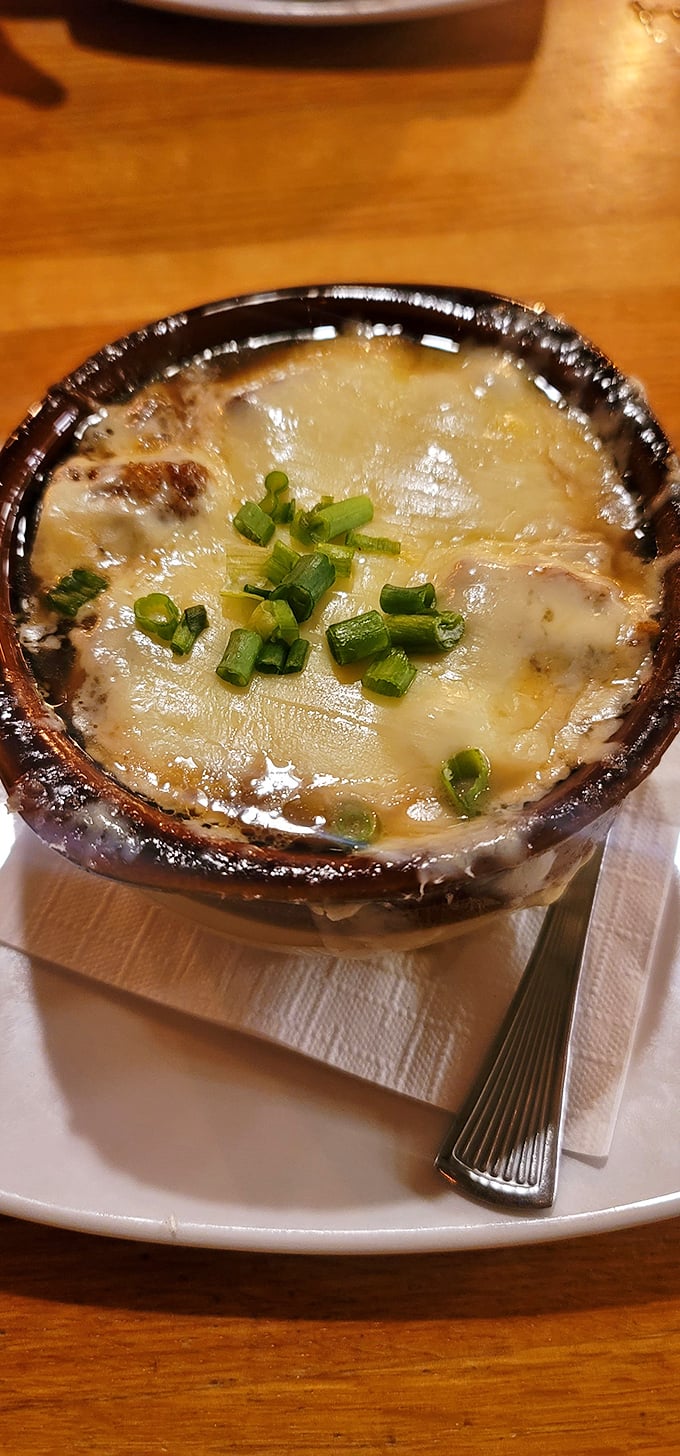This isn't just onion soup—it's a bubbling cauldron of comfort topped with a golden cheese canopy that stretches with each spoonful.