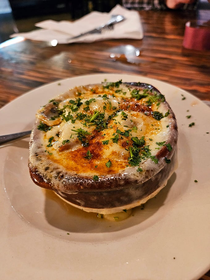 This isn't just French onion soup—it's a cheese-capped miracle in a crock, waiting for you to break through to the caramelized treasure below.