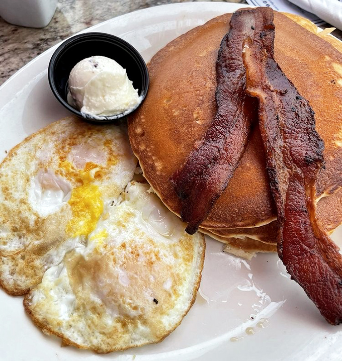 The pancake combo that launched a thousand return visits – golden discs of perfection with eggs and bacon that would make Ron Swanson weep with joy.