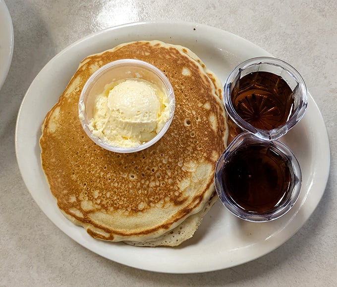 A pancake so perfectly golden it could win medals, topped with a scoop of butter and served with syrup—breakfast nirvana achieved.