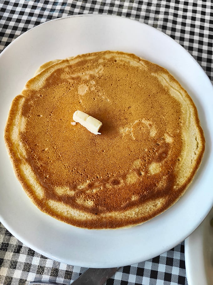 Behold the pancake in its natural habitat – golden, perfectly round, with butter slowly melting into its warm embrace. Simplicity at its most delicious.