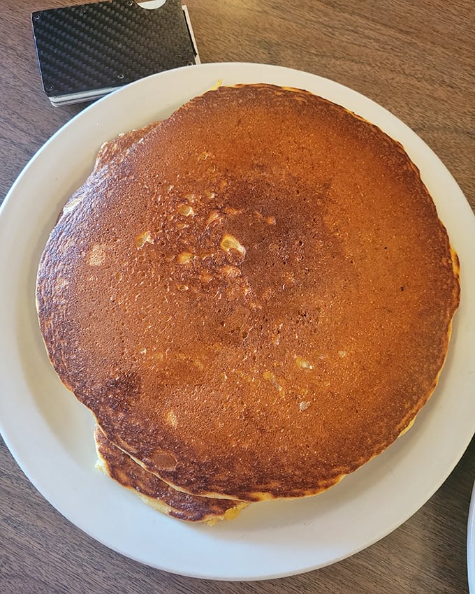 This pancake isn't just big—it's practically a frisbee of deliciousness that hangs over the plate edges, daring you to finish it all.