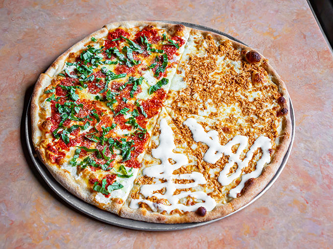 Half red sauce, half white sauce—this pizza doesn't believe in picking sides. The charred crust edges tell the story of proper wood-fired technique. 