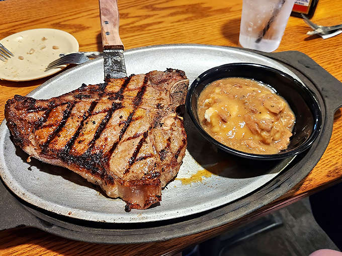 The porterhouse arrives like a challenge on a metal plate. That sizzle and that side of mushroom sauce? Game over.