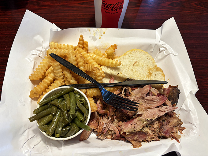 A tray of pulled pork perfection with those crinkle-cut fries that somehow make everything taste better, like comfort on a plate.