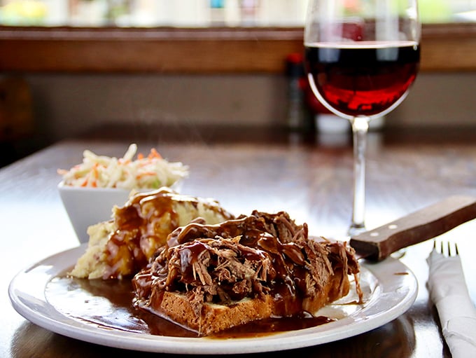The open-faced pulled pork sandwich isn't just a meal, it's an architectural marvel of tender meat and savory sauce on hearty bread.