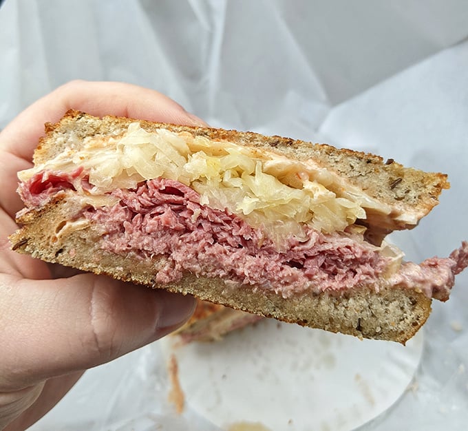 Behold the Reuben in its natural habitat—layers of corned beef and sauerkraut creating what can only be described as a sandwich symphony.