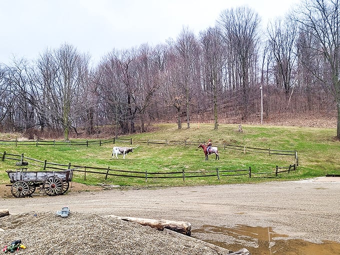 Rural charm abounds with horses grazing peacefully in nearby paddocks, creating a pastoral backdrop for the giant nodding chef.