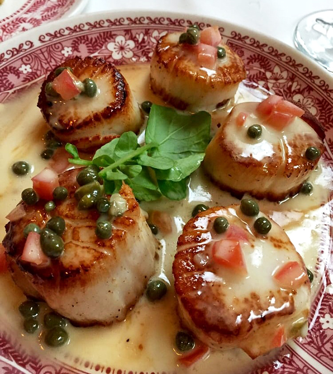 These scallops aren't just seared – they're transformed into buttery medallions of oceanic perfection, dressed with capers in a sauce worth sopping up with bread.