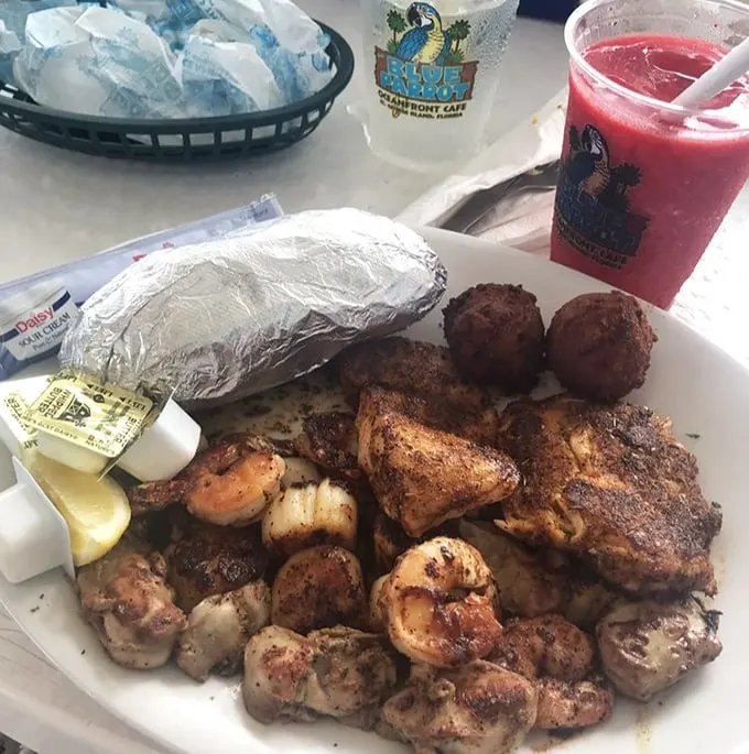 Blackened perfection meets Gulf shrimp in a plate that whispers, "Cancel your afternoon plans." That red drink isn't optional—it's essential.