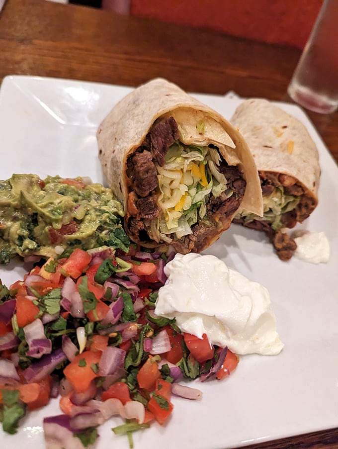 Behold the burrito in its natural habitat—surrounded by fresh pico de gallo, guacamole, and sour cream like a protein-packed celebrity with its entourage.