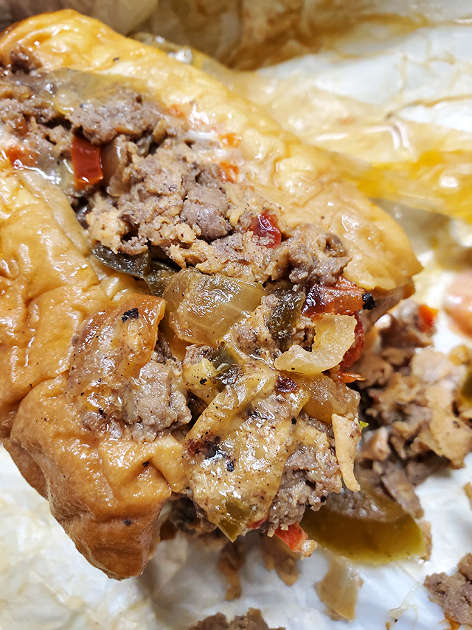 The cross-section reveals the truth – perfectly caramelized meat, melted cheese, and those sweet onions nestled in a roll that's both sturdy and yielding.