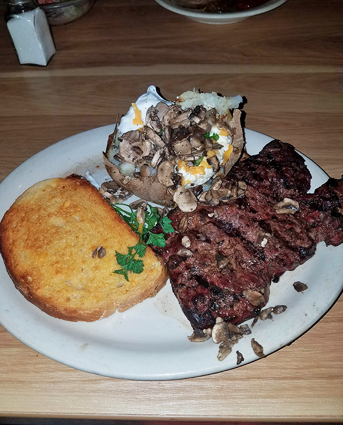 This steak and loaded baked potato plate isn't just dinner—it's therapy on a white ceramic plate. The mushroom garnish is just showing off.