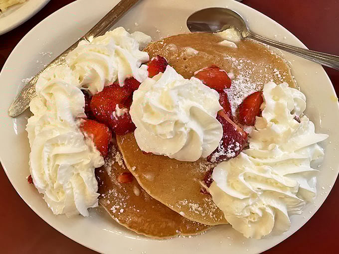 These pancakes don't just have strawberries—they've formed a delicious alliance. The whipped cream ambassadors are negotiating peace between your taste buds and diet.